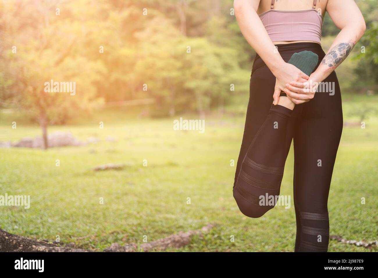 Young woman runner stretching legs before running Stock Photo - Alamy