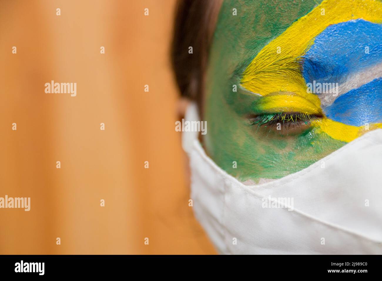 child with a mask with his face painted with the flag of Brazil Stock ...