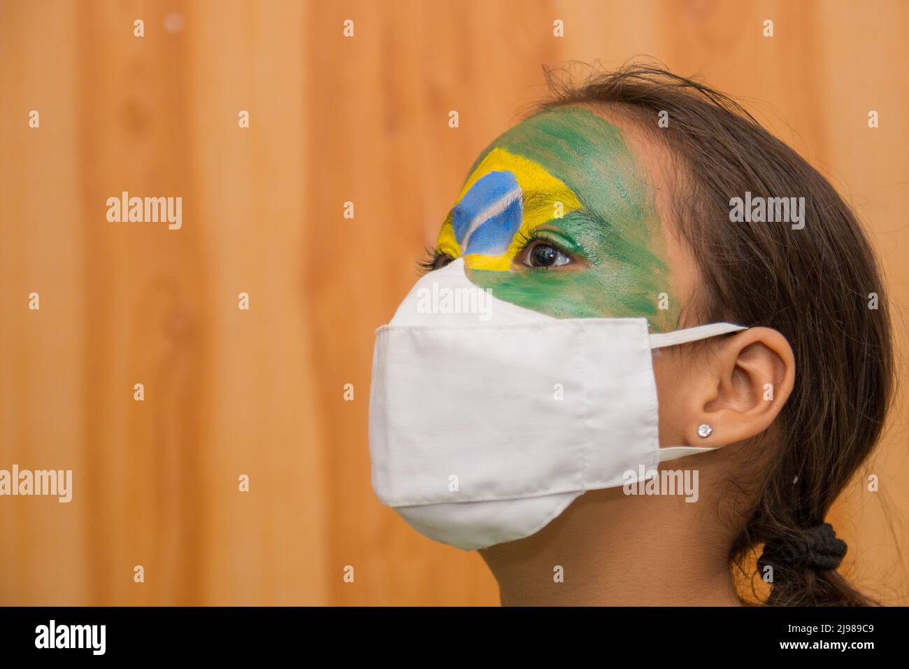 child with a mask with his face painted with the flag of Brazil Stock ...