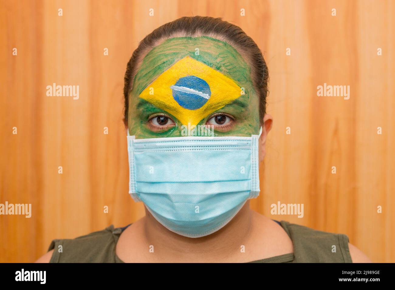 Woman with the flag of Brazil painted on her face with a blue hospital ...