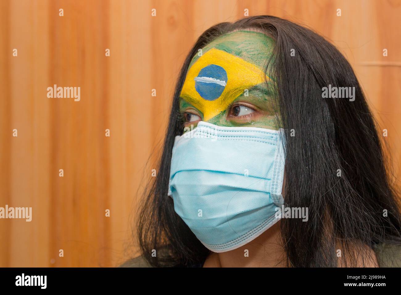 Woman with the flag of Brazil painted on her face with a blue hospital ...