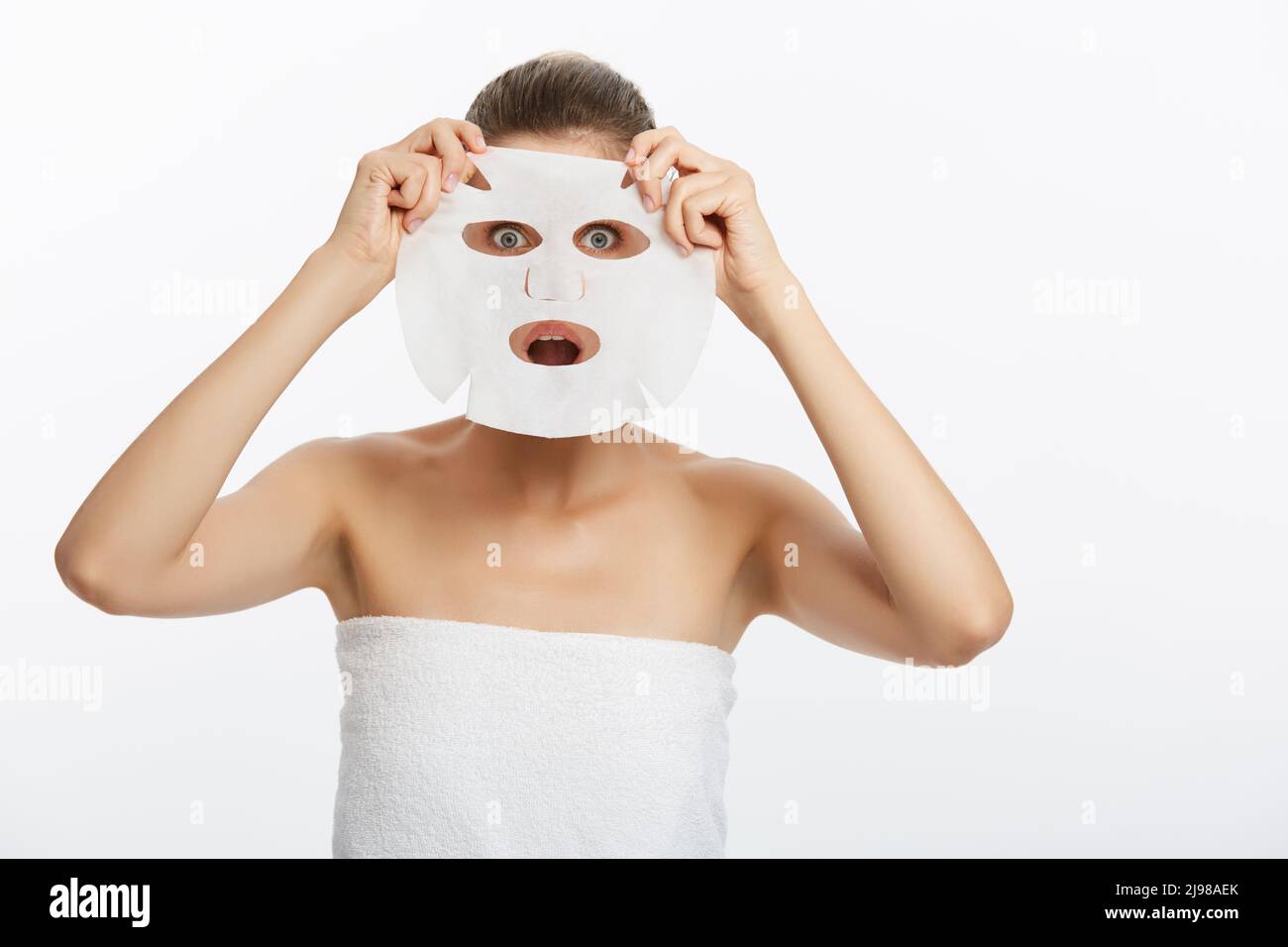 Young girl with facial mask looking at camera over white background ...