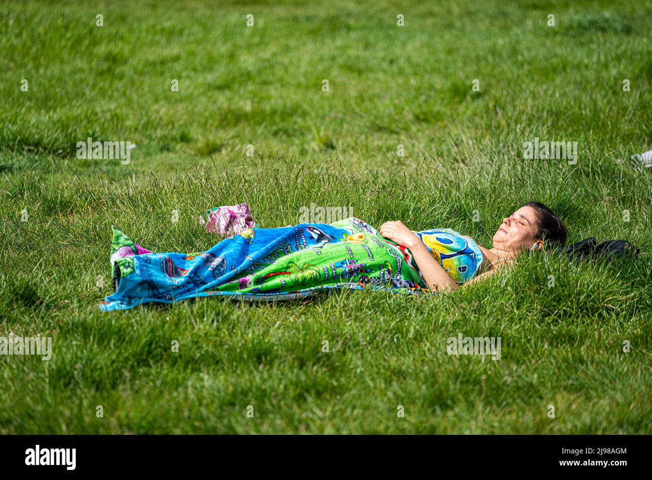 London UK, 21 May 2022. A woman sunbathing in the spring afternoon ...