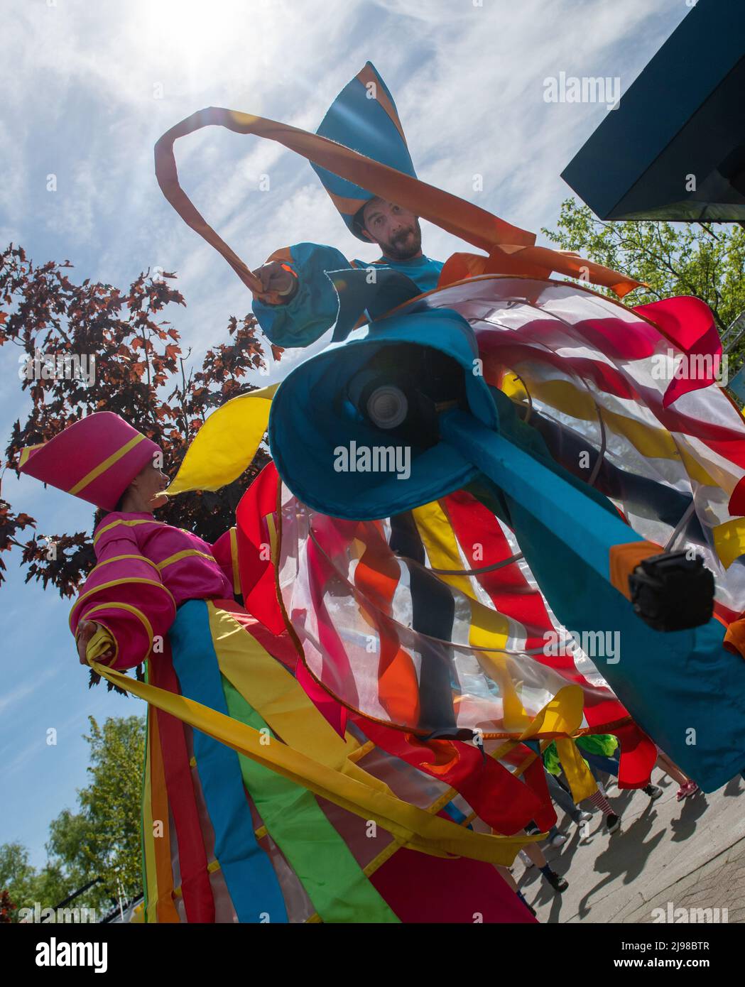 21 May 2022, Bavaria, Günzburg: A colorfully dressed stilt walker ...