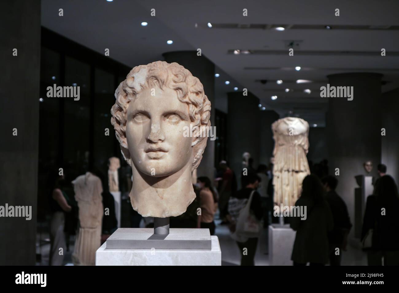 Visitors pass by the head of a statue of Alexander the Great in the ...