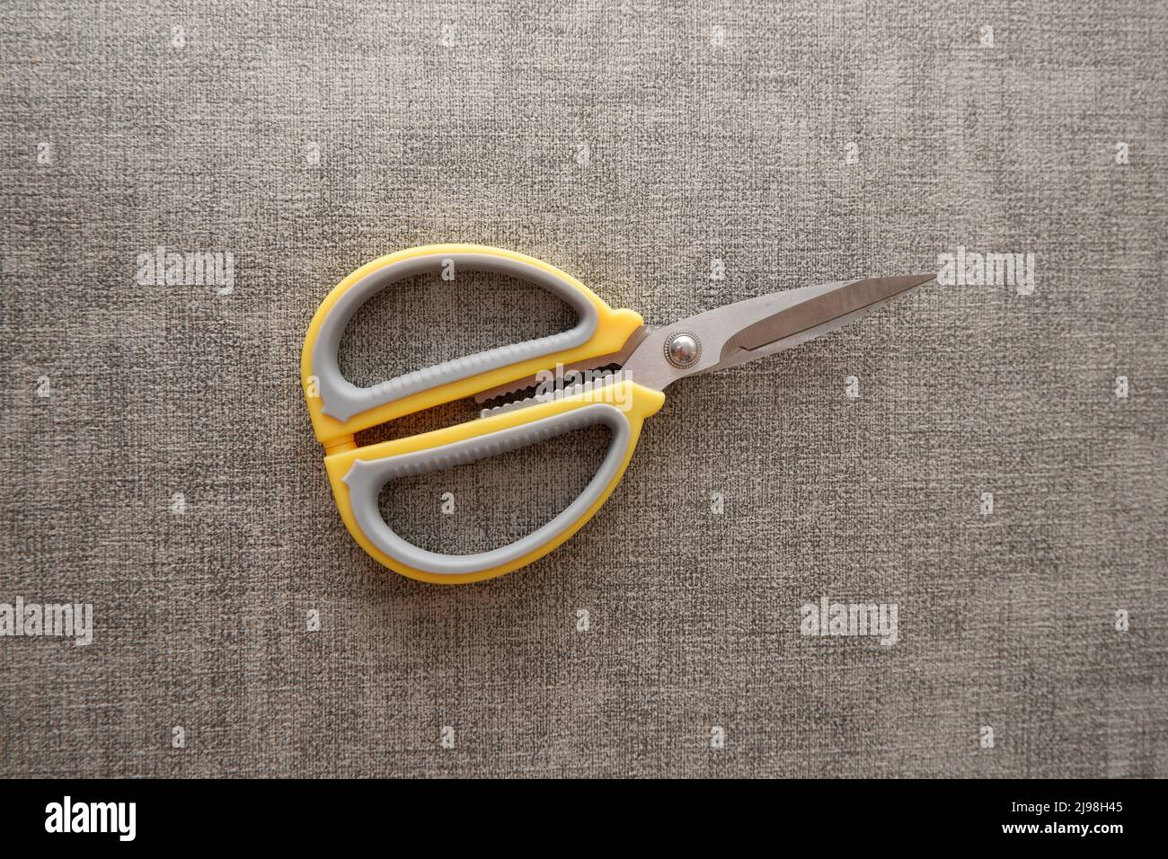 Yellow handle scissor on a grey background Stock Photo - Alamy