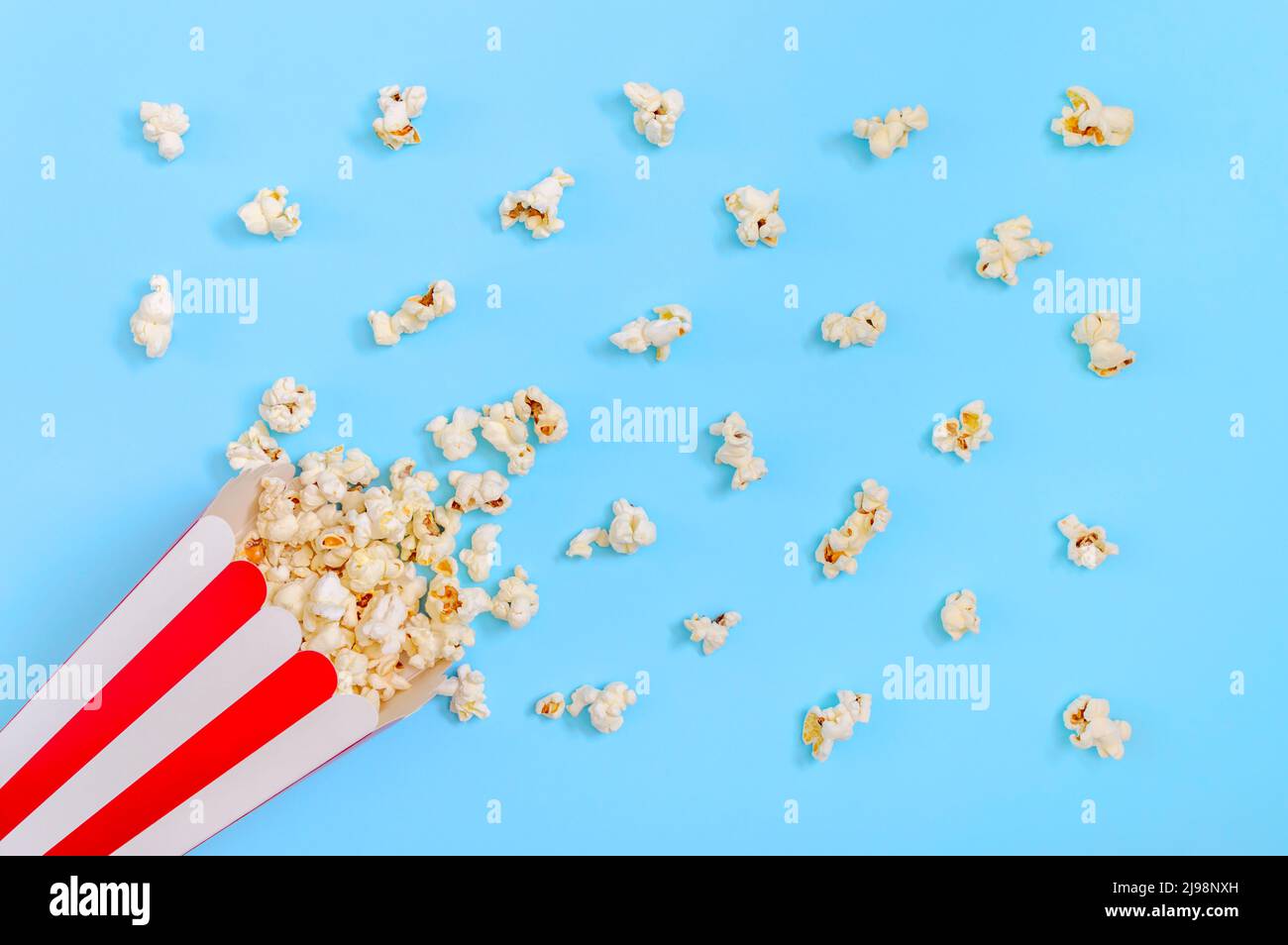 Striped cup with popcorn on color background. Paper box with snack on ...