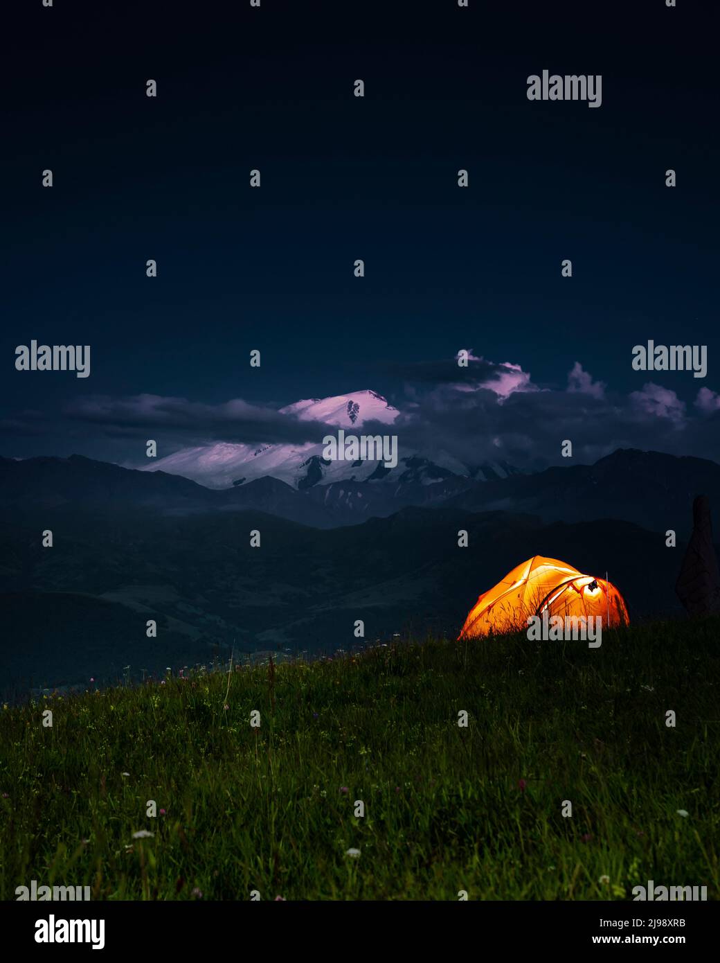 Camping in the mountains with tent standing on a hill, night and sunset ...