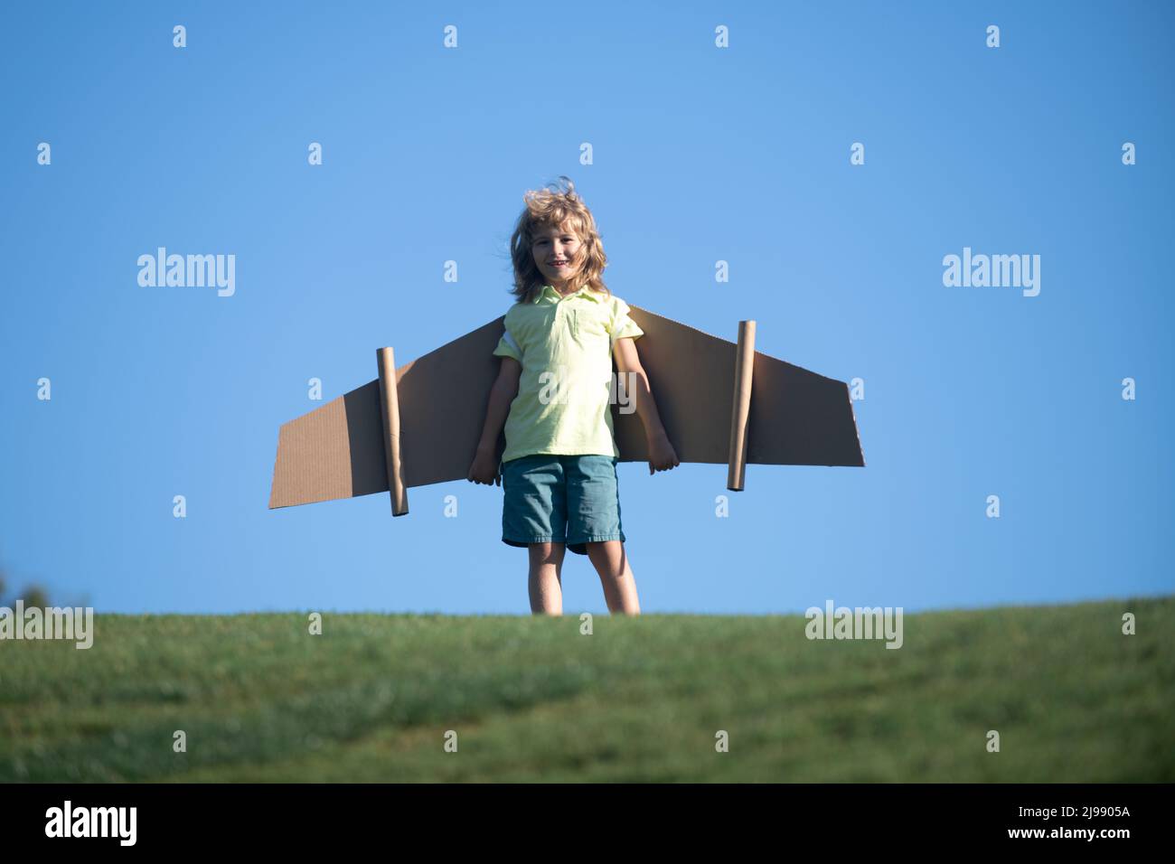 Child playing with cardboard toy wings in the park. Concept of children ...