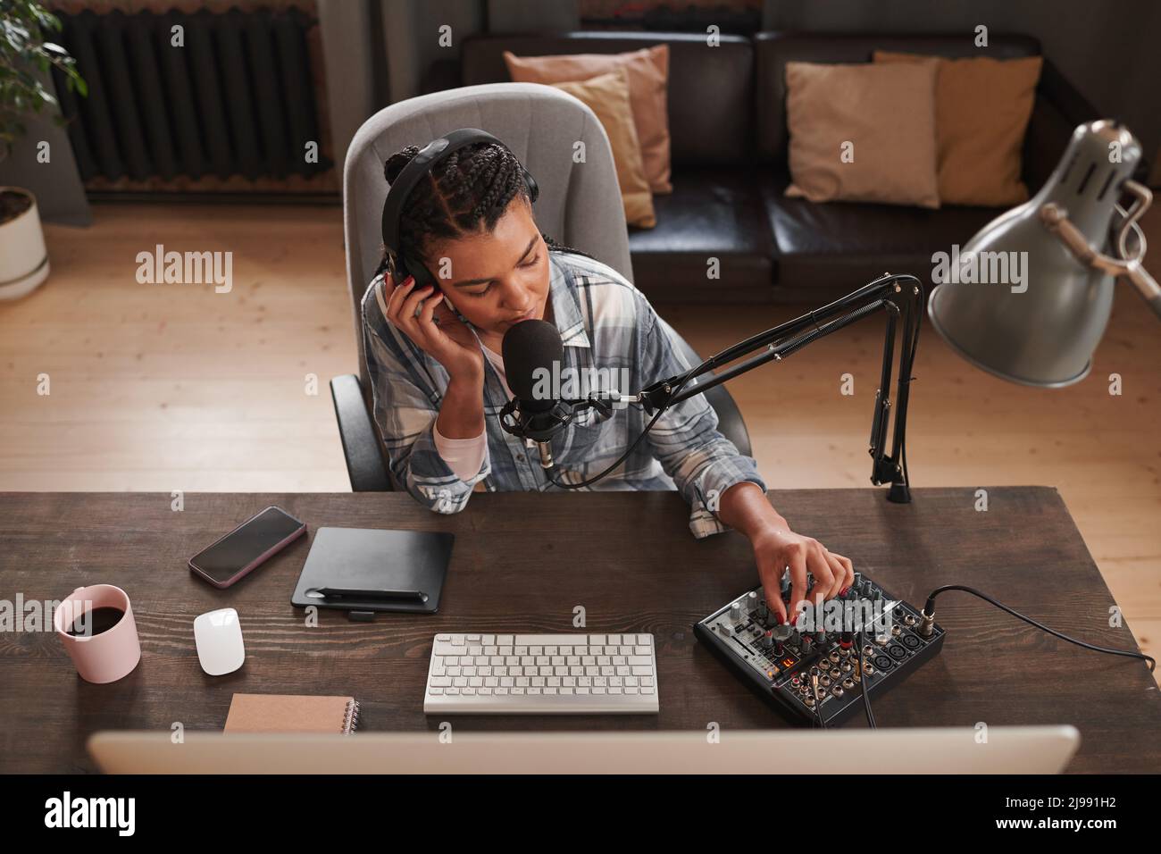 High angle view portrait of young woman sitting at wooden table in loft ...