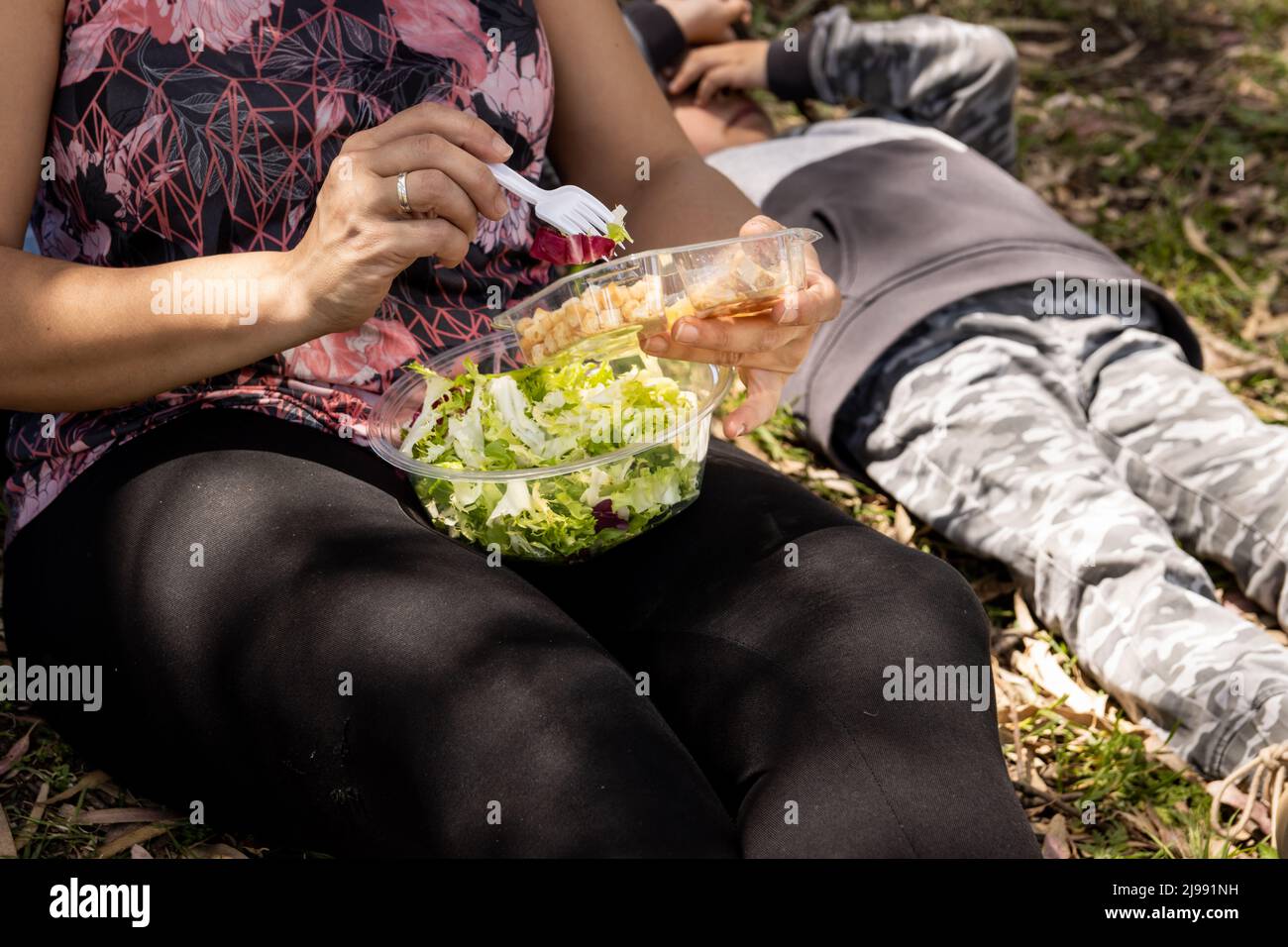 Woman eating salad in the field in plastic container Stock Photo - Alamy