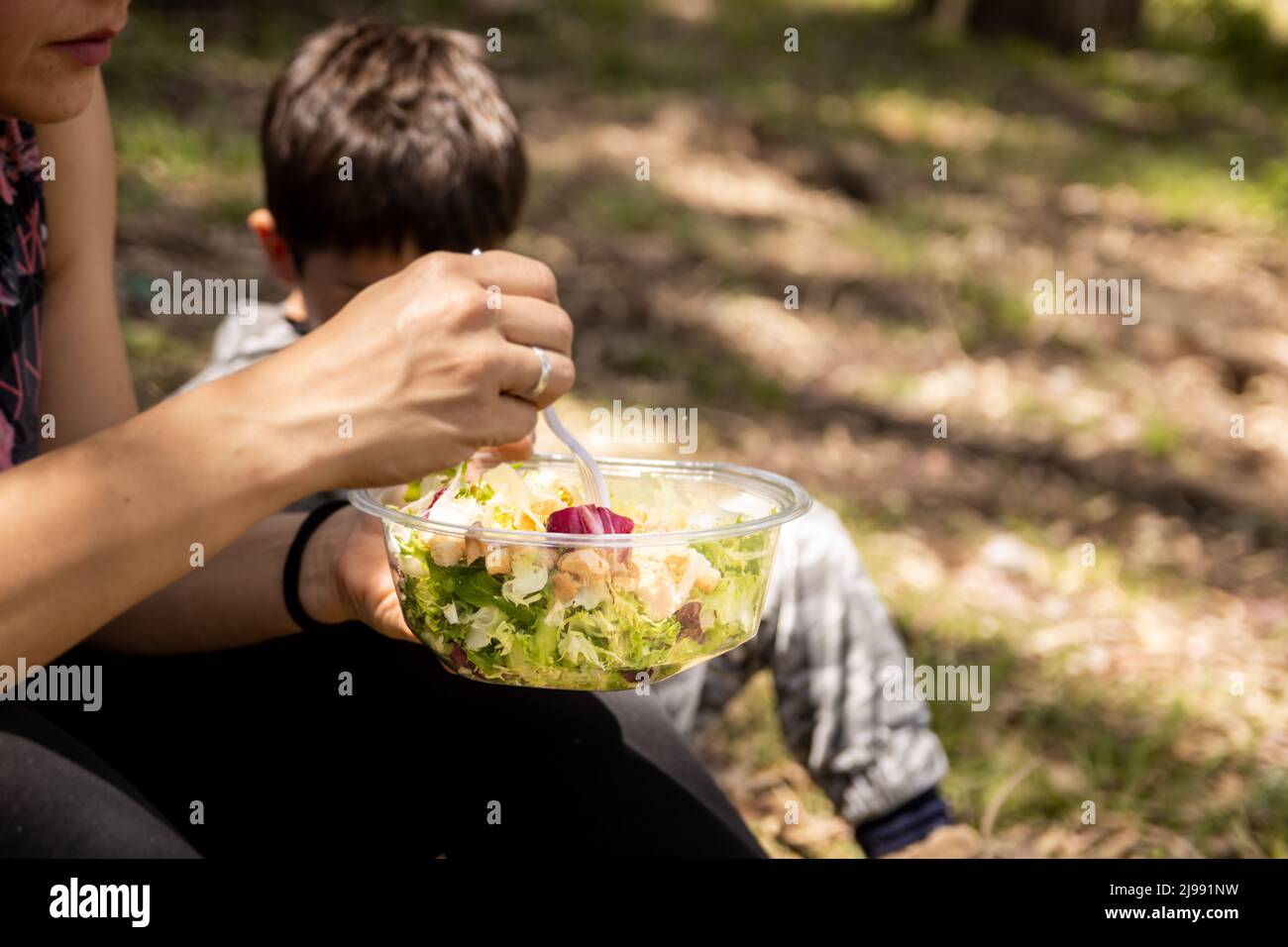 Woman eating salad in the field in plastic container Stock Photo - Alamy