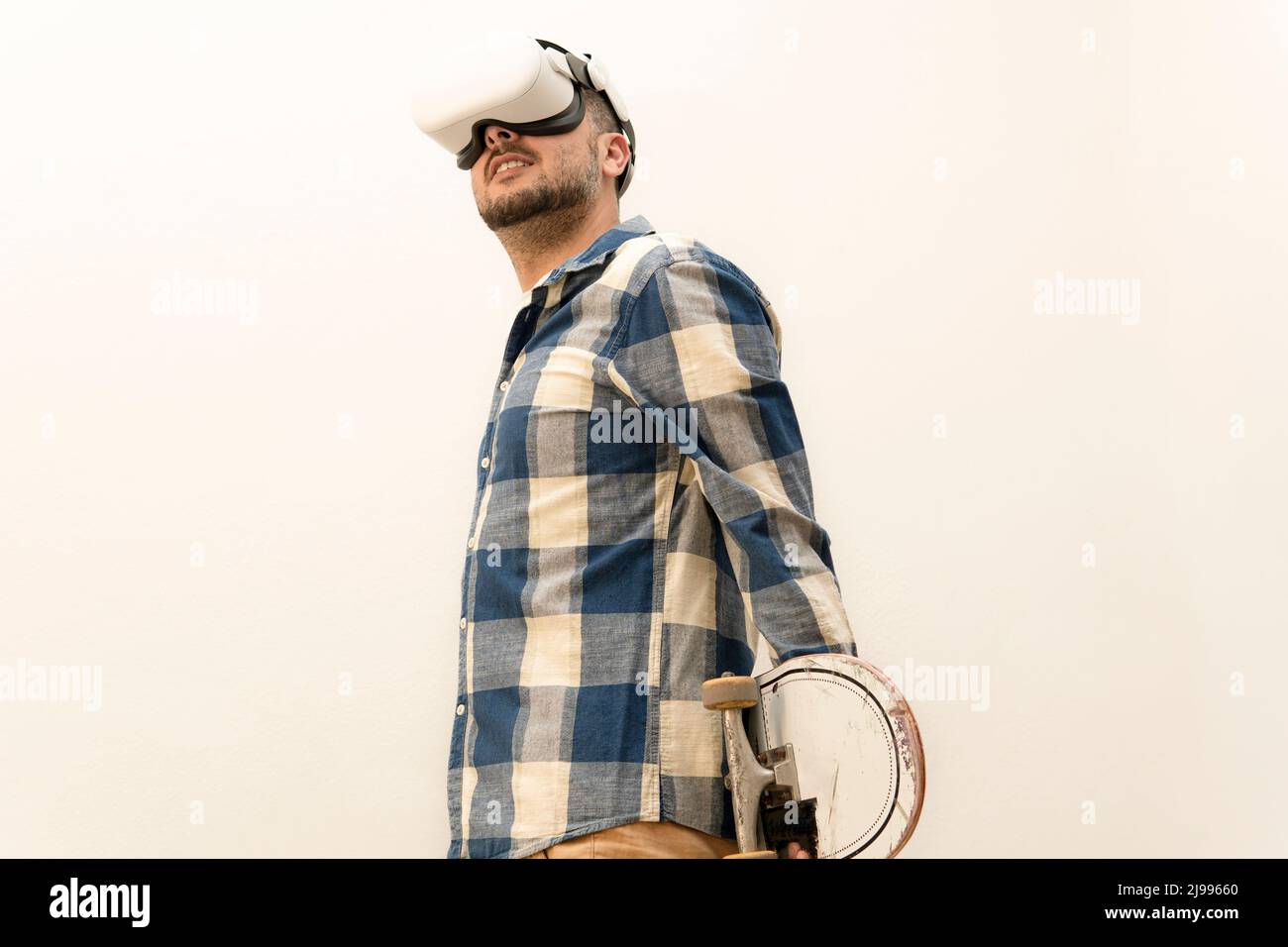 Man posing clutching his skateboard backwards on his back with his ...