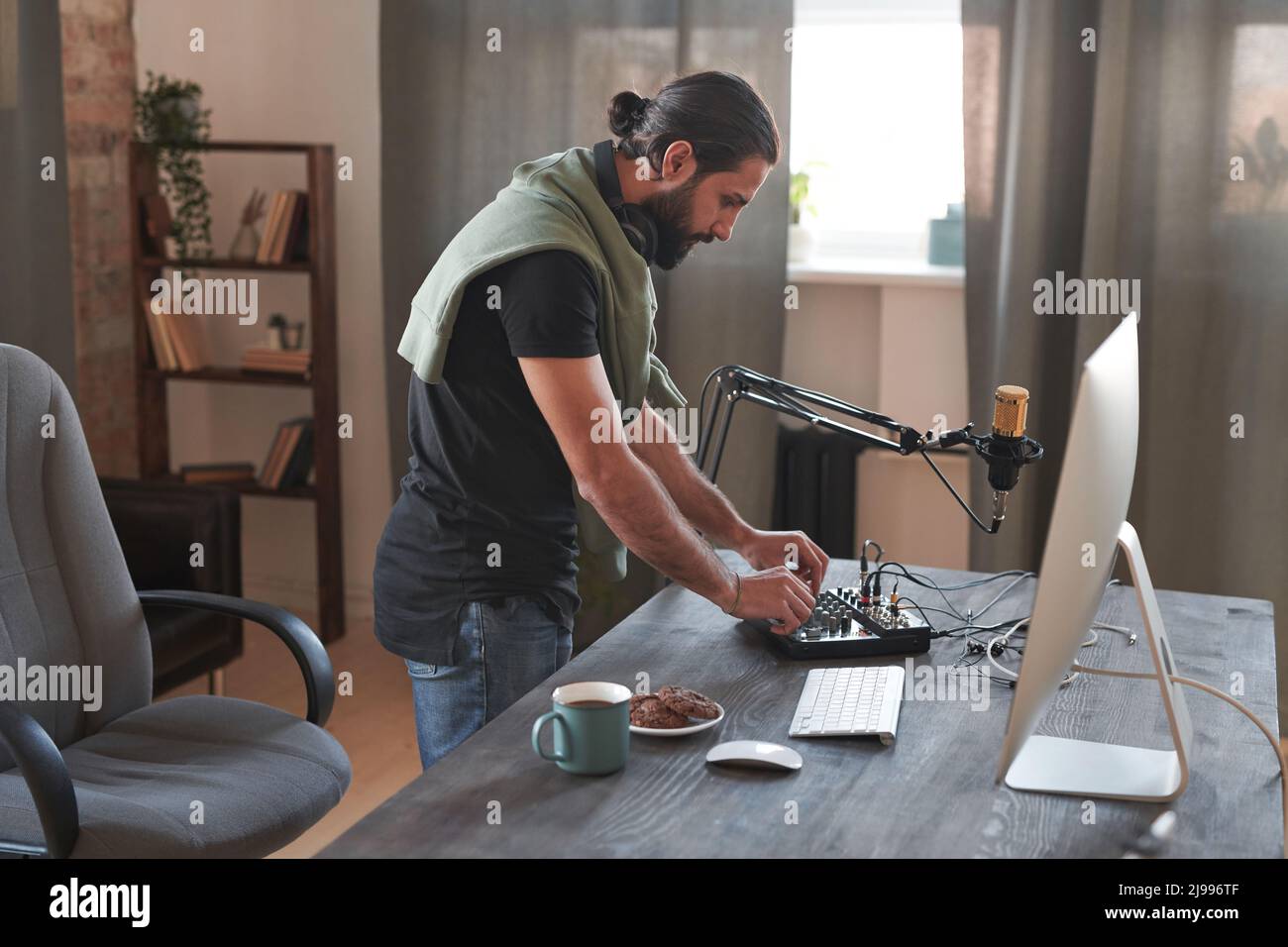 Medium Long Shot Of Young Man Adjusting Audio Mixer Setting Sound In