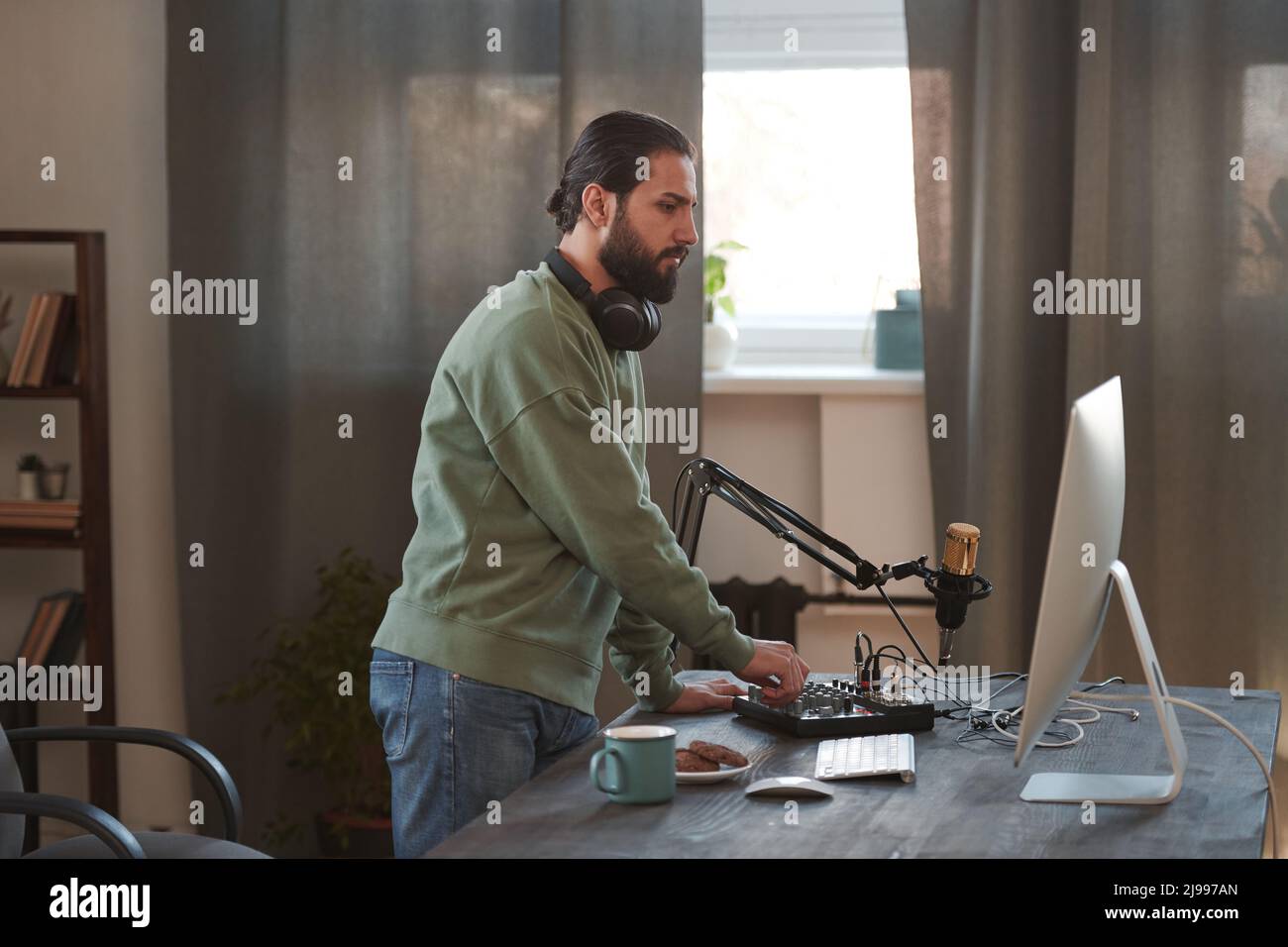 Horizontal long side view shot of young bearded man adjusting sound in ...