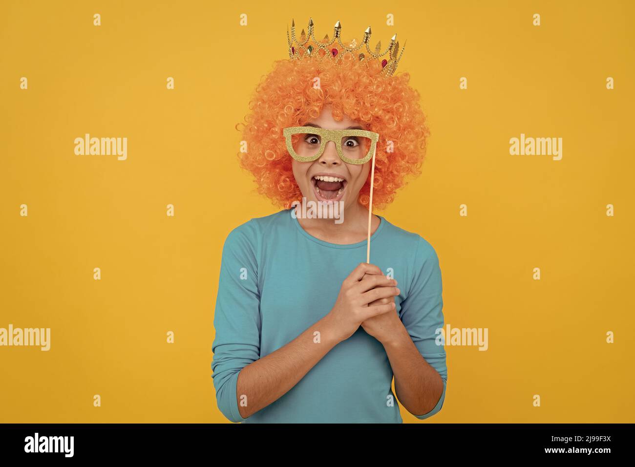 surprised selfish child girl in curly wig and princess diadem hold ...