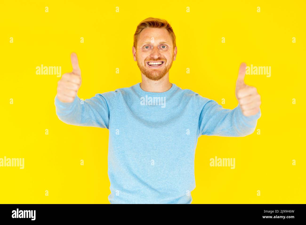 Happy man doing thumb up with hands over yellow isolated background ...