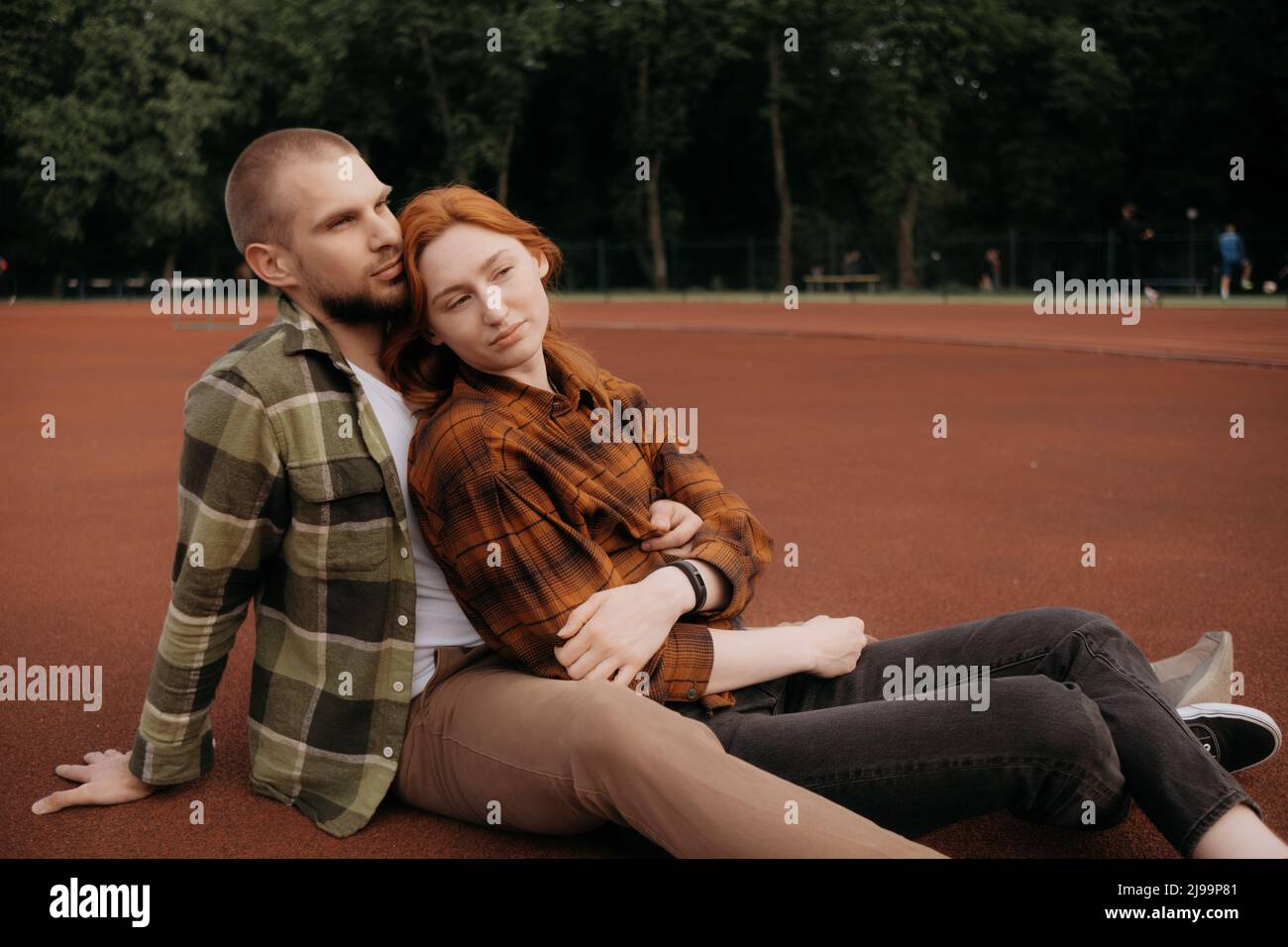 lovers sit in a hug on a red coating Stock Photo - Alamy