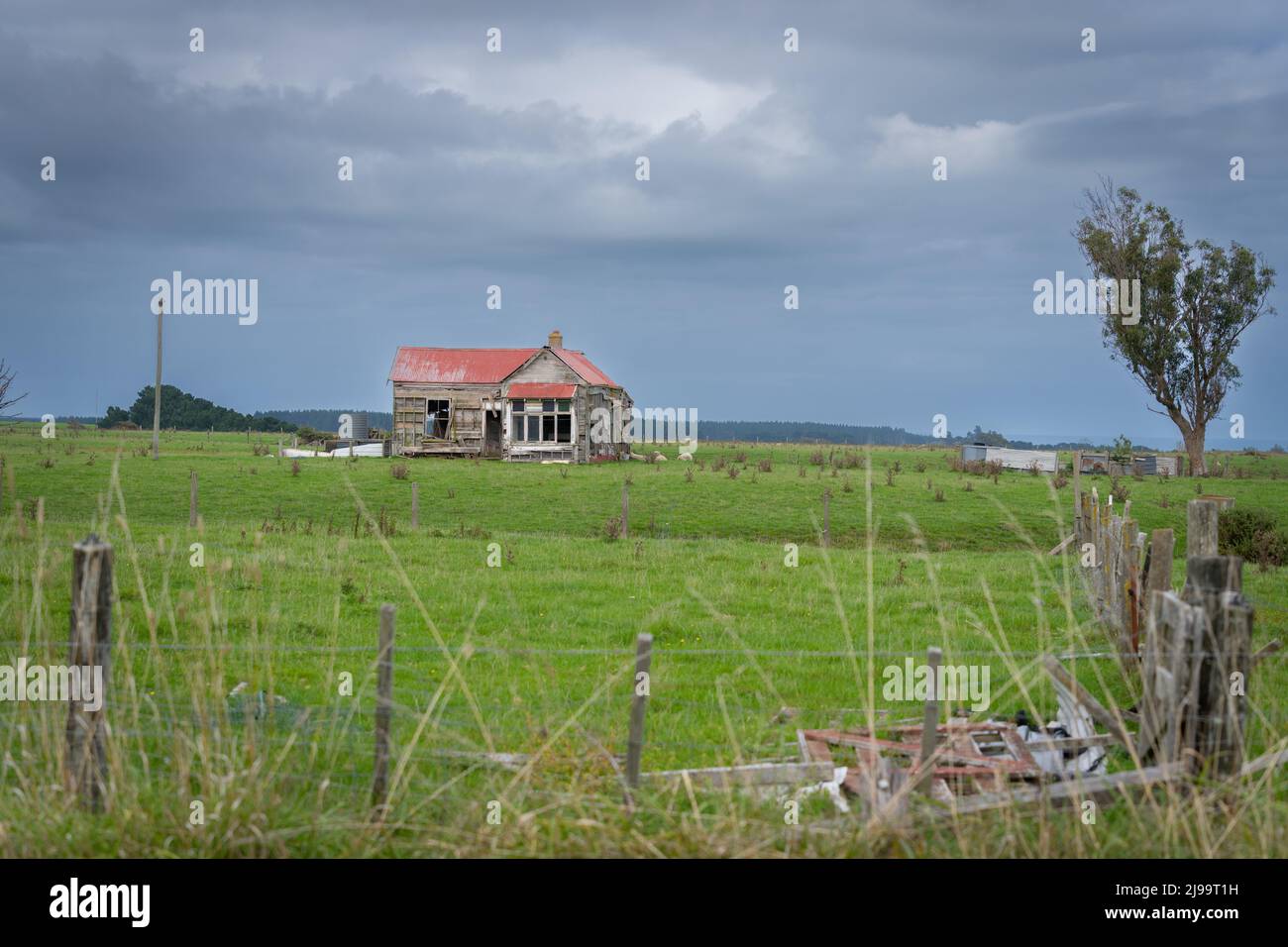 Deserted house in field beyond fence and green grass Stock Photo - Alamy