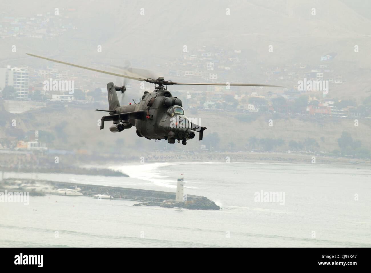 A helicopter Mil Mi-25 of the Peruvian Air Force, flies over the coast ...