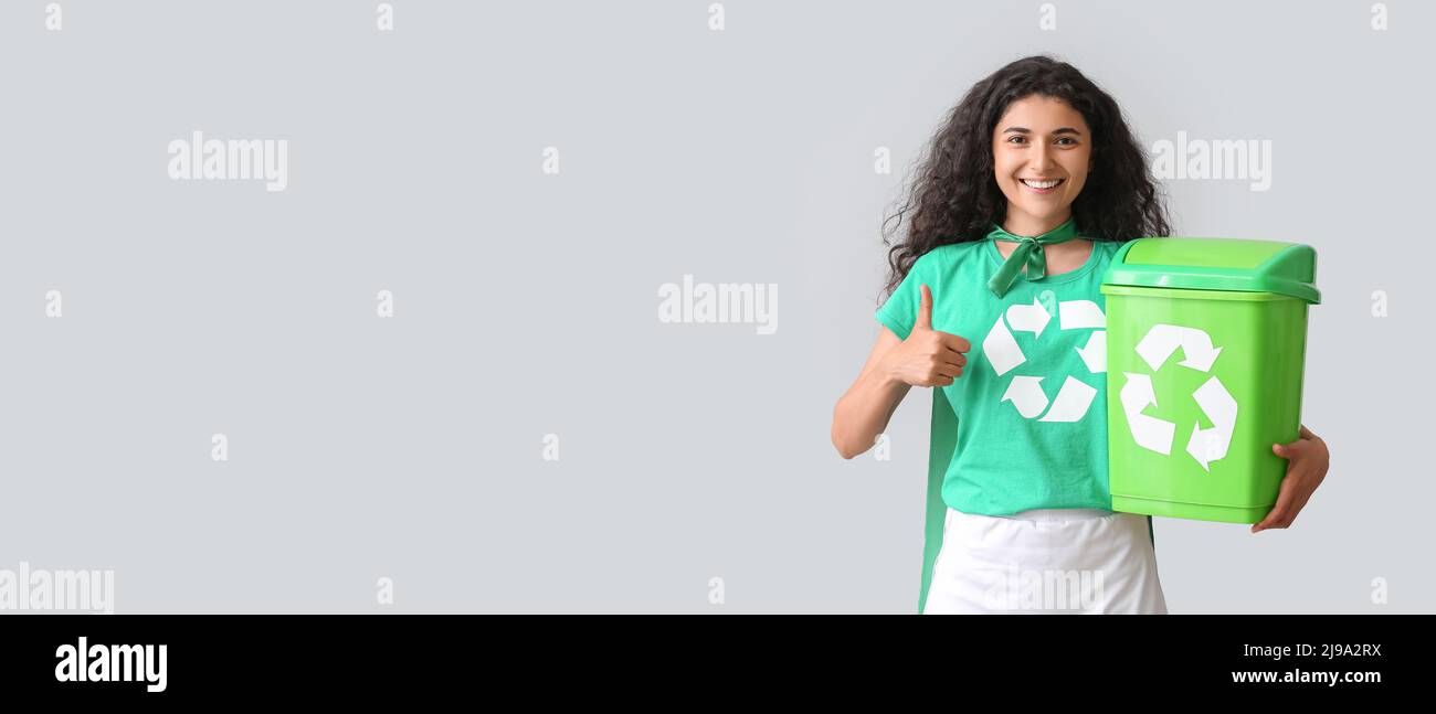 Woman dressed as eco superhero with trash bin on light background ...