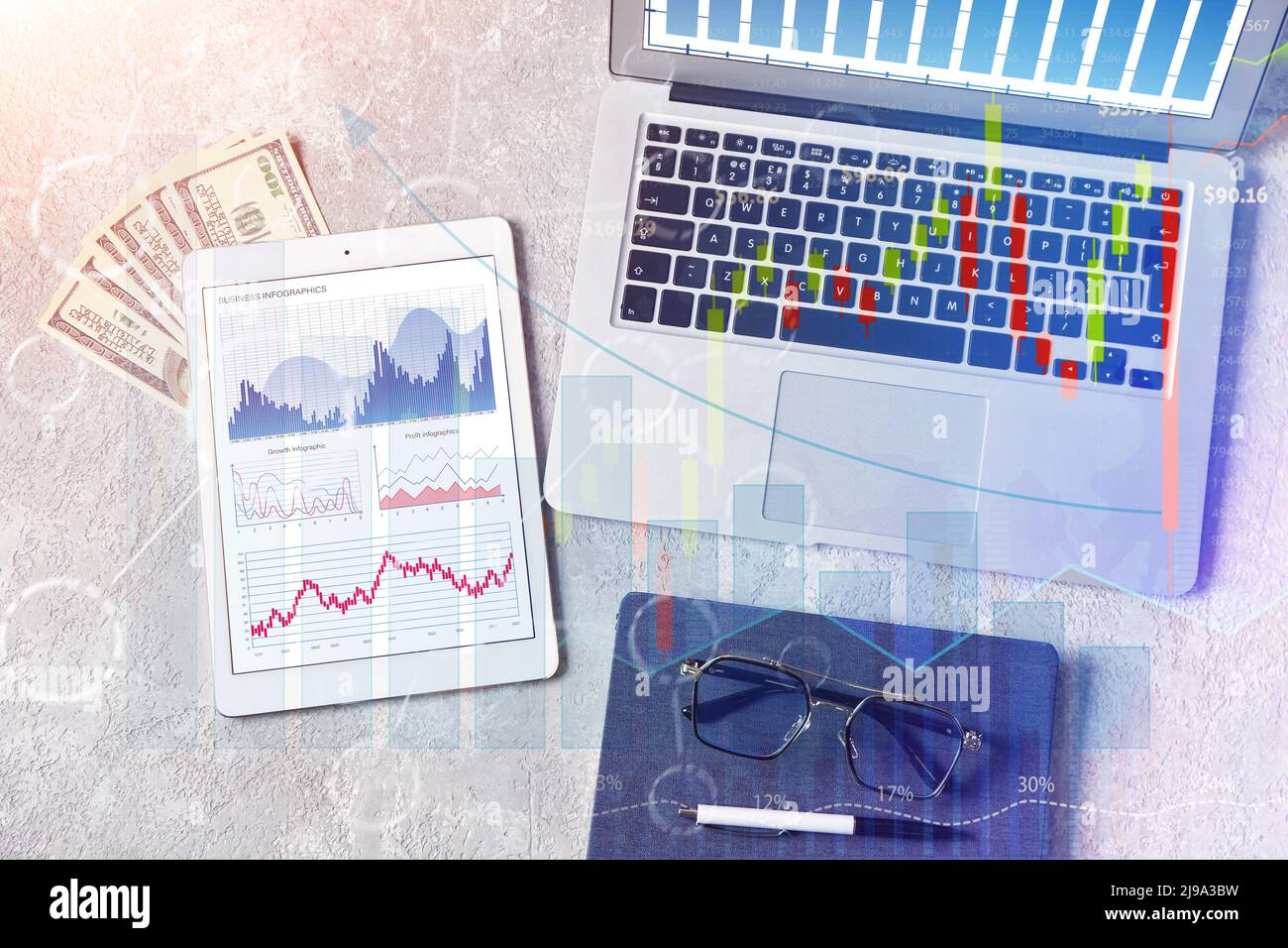 Laptop and tablet computers with diagrams on screens and money with ...