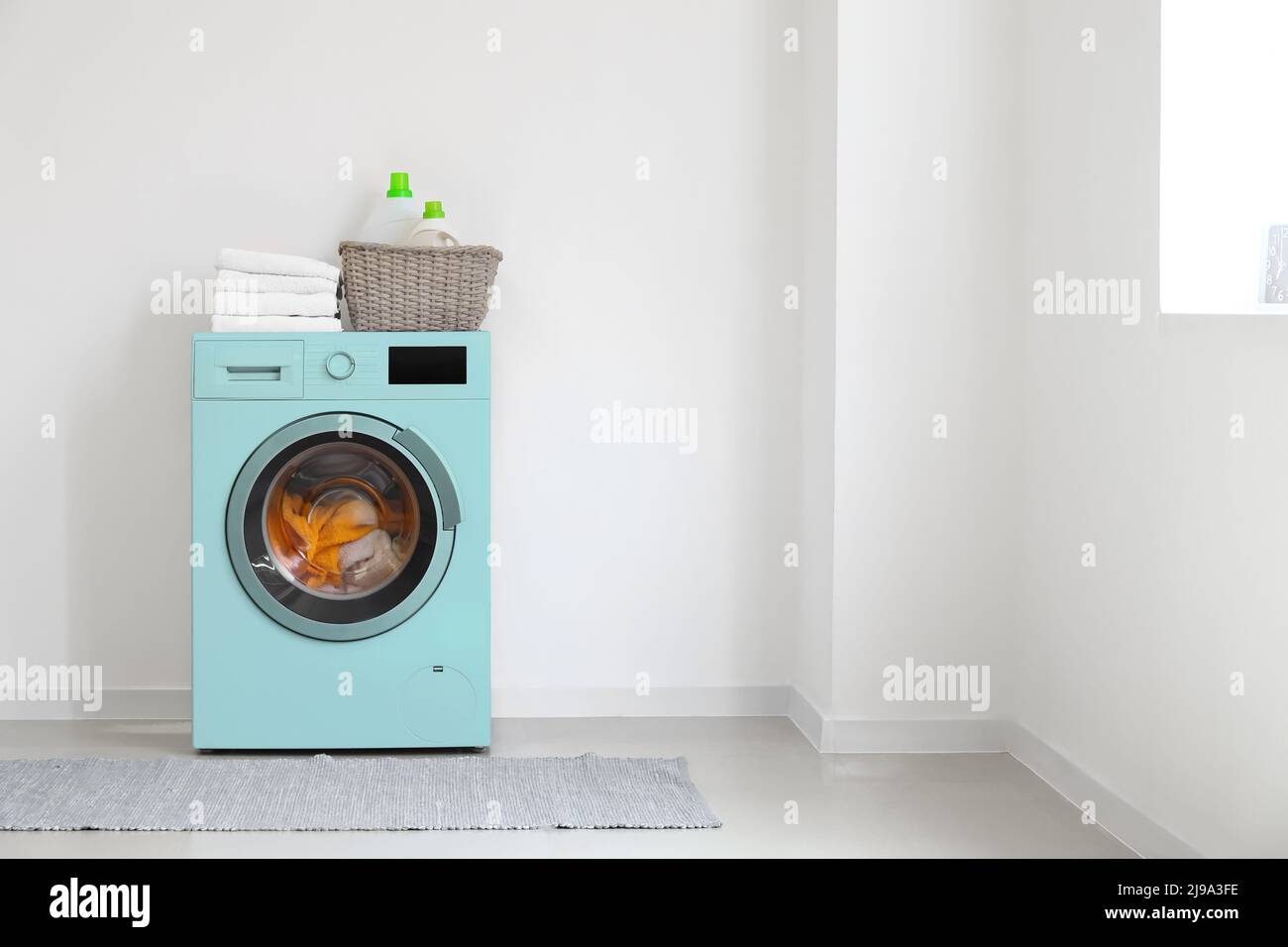 Modern turquoise washing machine near white wall in laundry room Stock ...