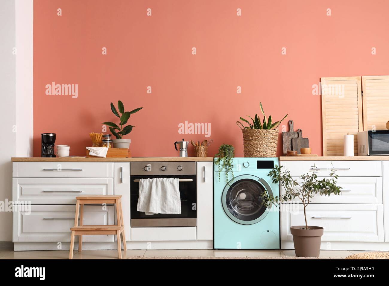 Interior of stylish kitchen with washing machine, oven and folding ...