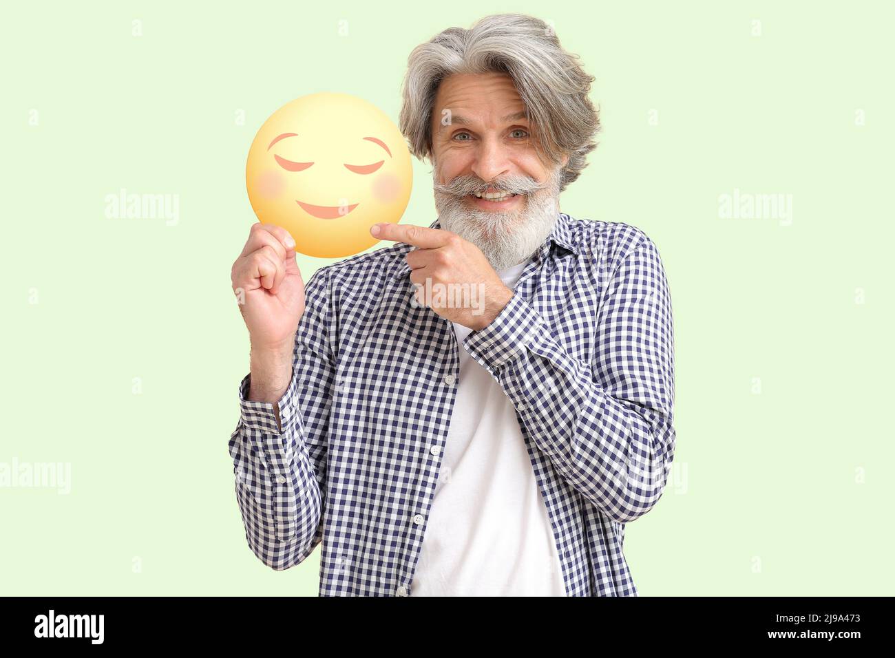 Happy senior man holding smiling emoticon on light color background ...