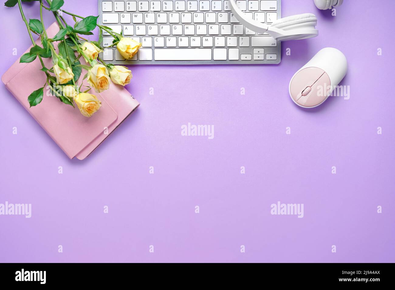 Computer keyboard with mouse, headphones, roses and notebook on lilac ...