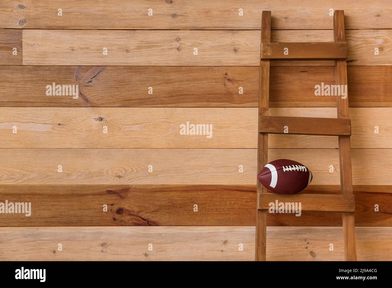 Rugby ball on ladder near wooden wall Stock Photo - Alamy