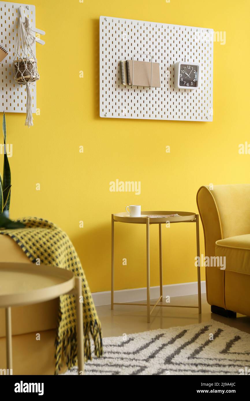 Pegboard with notebooks and clock on color wall in room Stock Photo - Alamy