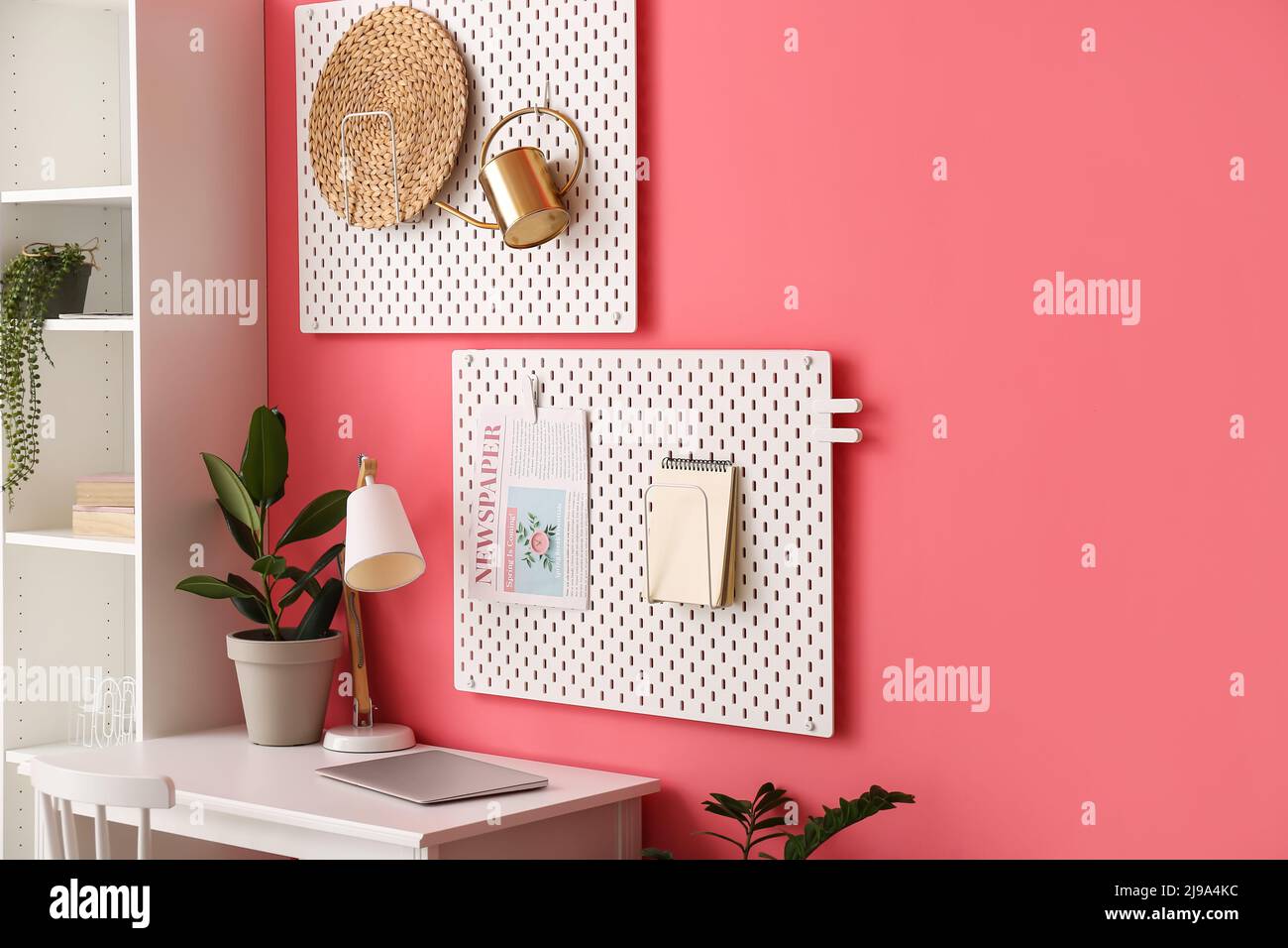 Pegboards and workplace with modern laptop near color wall in room ...