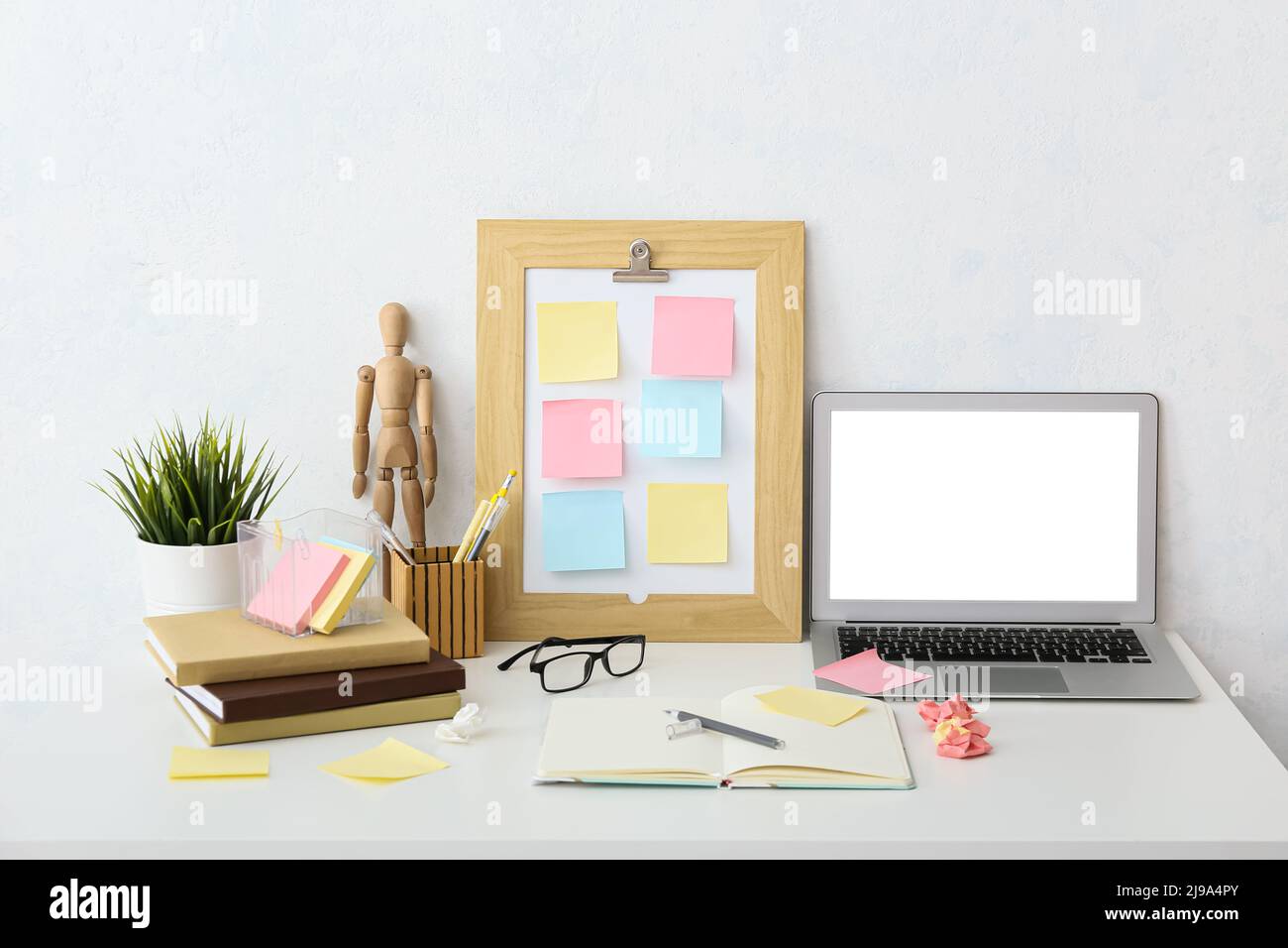 Workplace with laptop, mood board, sticky notes, notebooks, eyeglasses ...