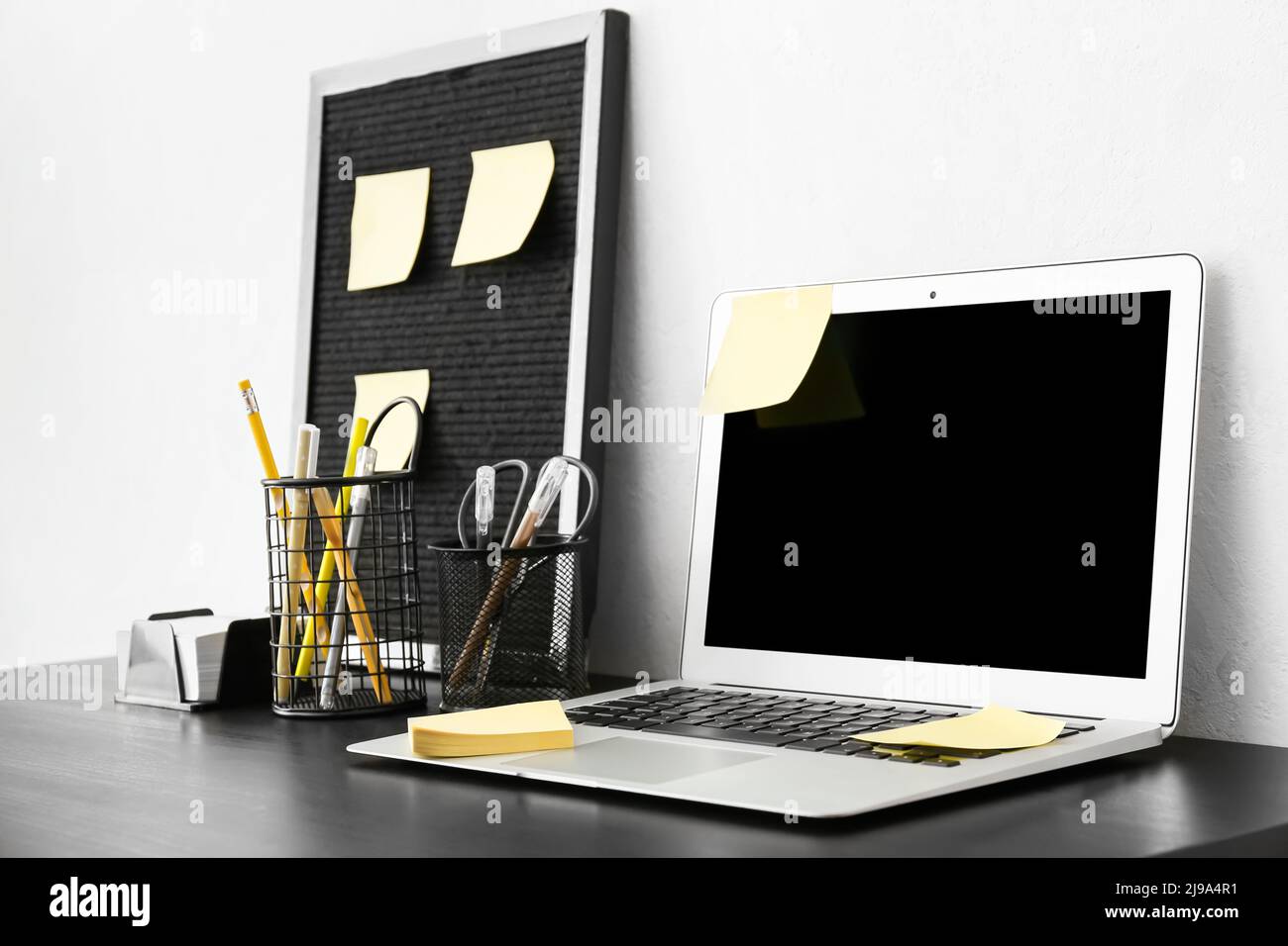 Modern laptop, blank sticky notes and holders with stationery supplies ...