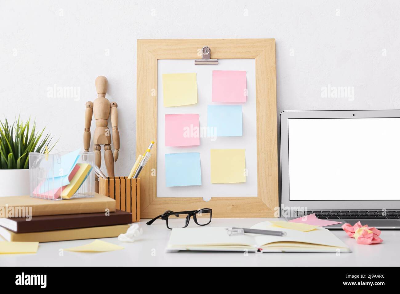 Workplace with mood board, sticky notes, laptop, crumpled paper and ...