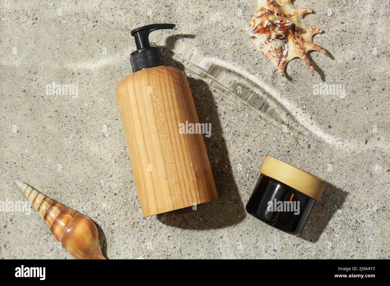 Dispenser bottle, jar of cosmetic product and seashells in water on ...