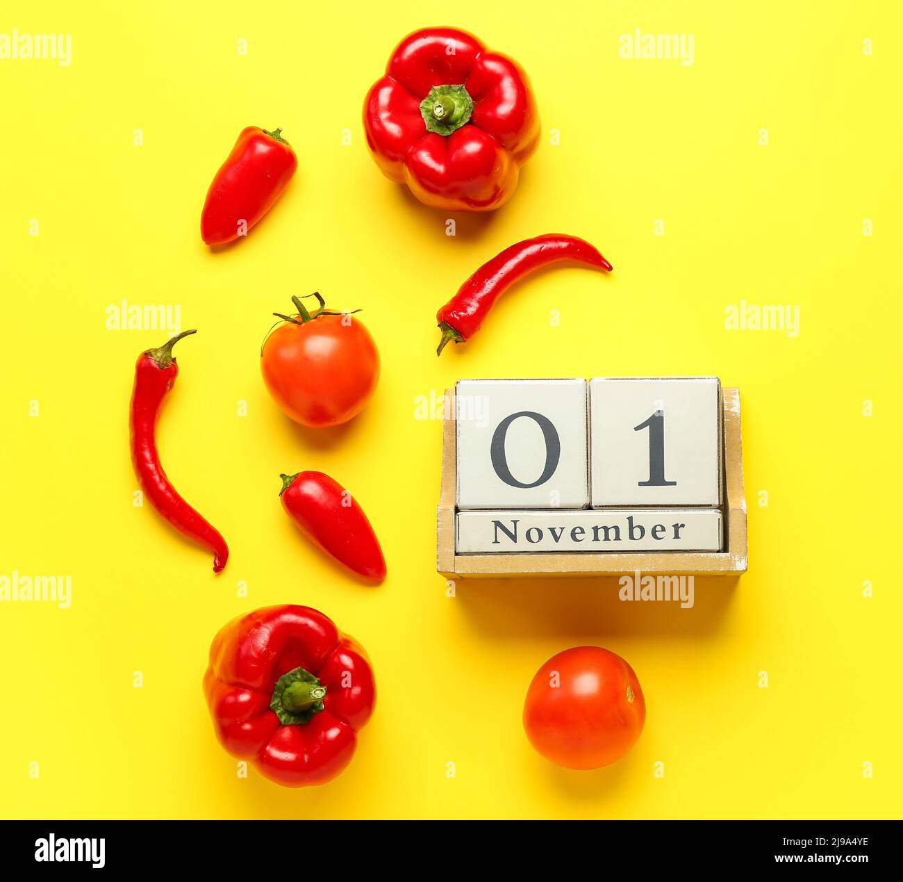 Wooden cube calendar with date NOVEMBER 1 and vegetables on yellow ...