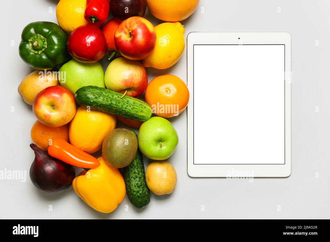 Different fruits, vegetables and tablet computer on grey background ...