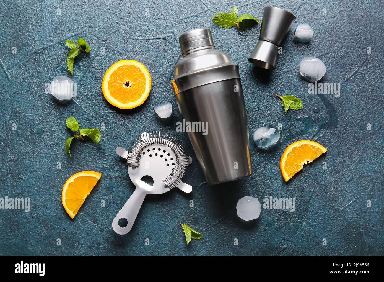 Strainer, cocktail shaker, double jigger and ingredients on dark ...