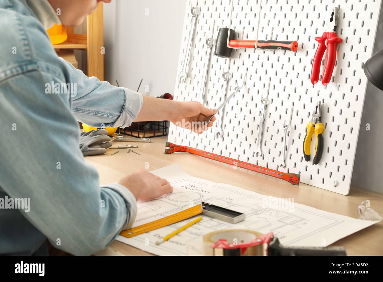 Man taking spanner from pegboard with tools in workshop Stock Photo - Alamy