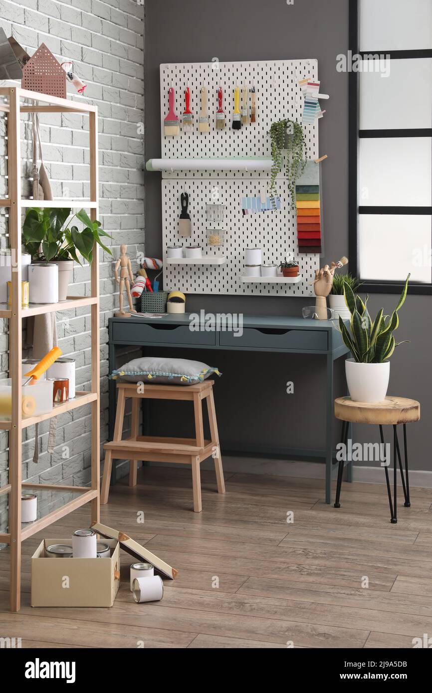 Modern decorator's workplace with different tools near grey brick wall ...