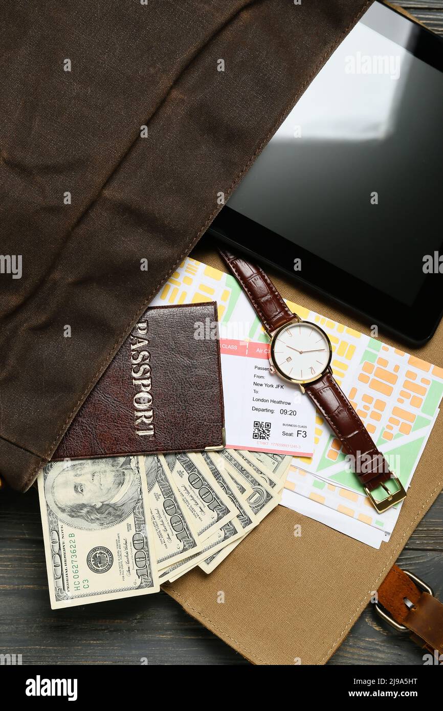 Bag with guide's belongings and tablet computer on dark wooden ...