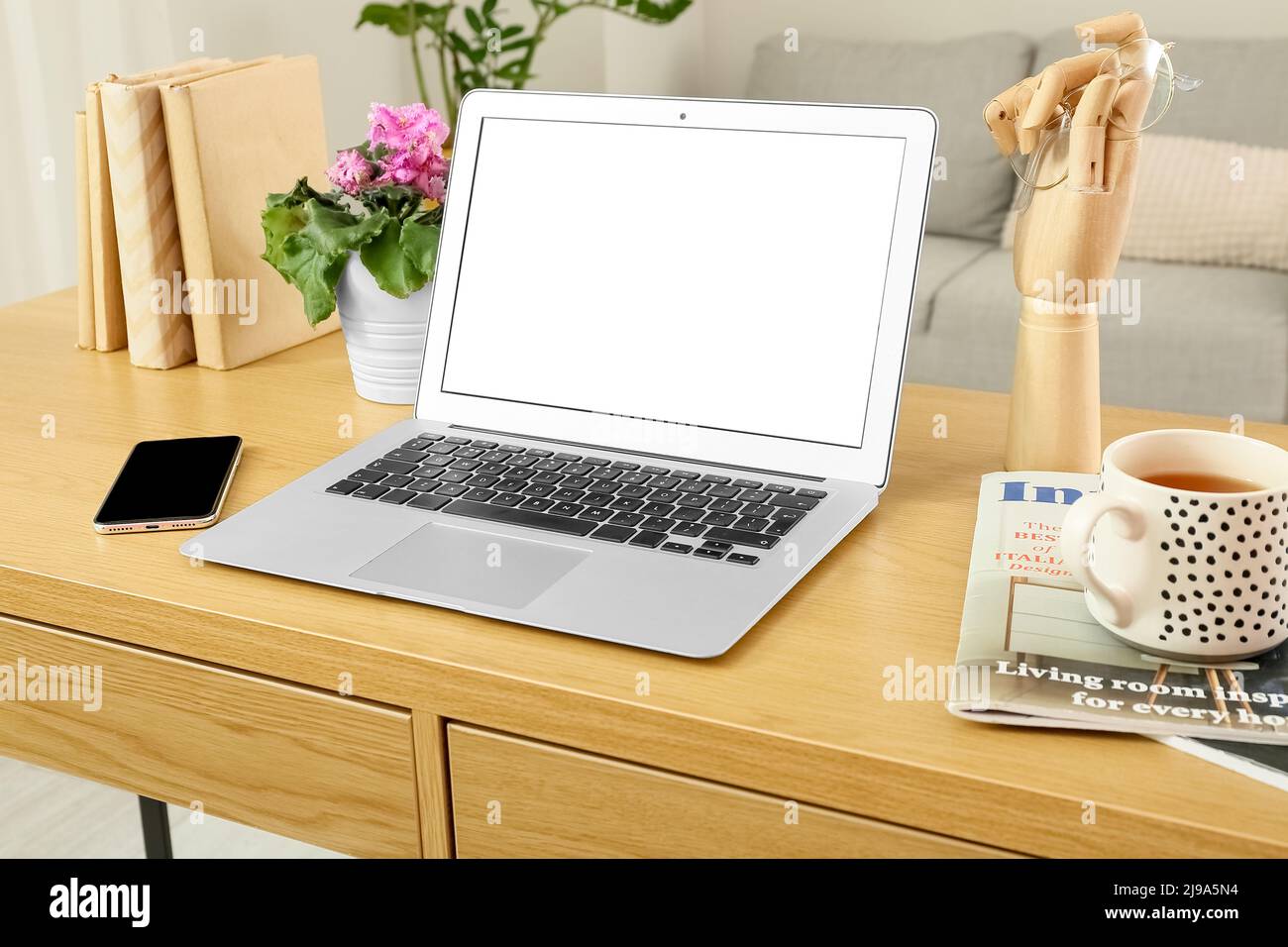 Workplace with modern laptop, mobile phone, cup and magazines in room ...