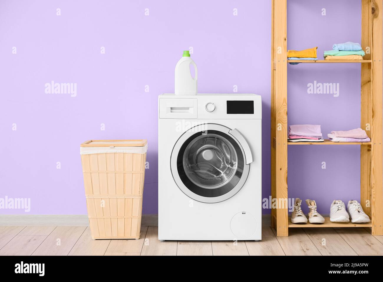 Washing machine, basket and shelf unit with clothes near color wall in ...