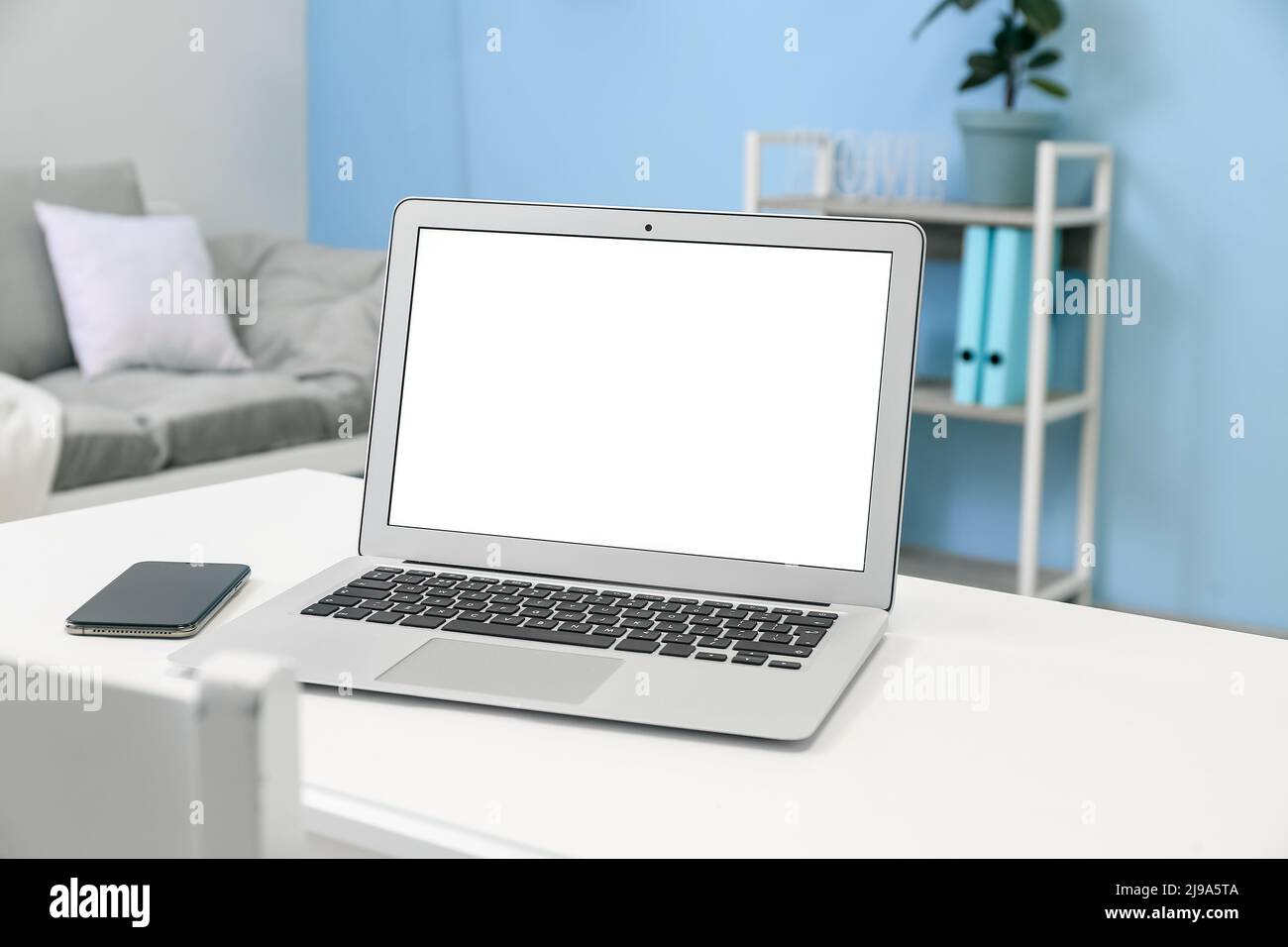 Modern laptop and mobile phone on table in room Stock Photo - Alamy