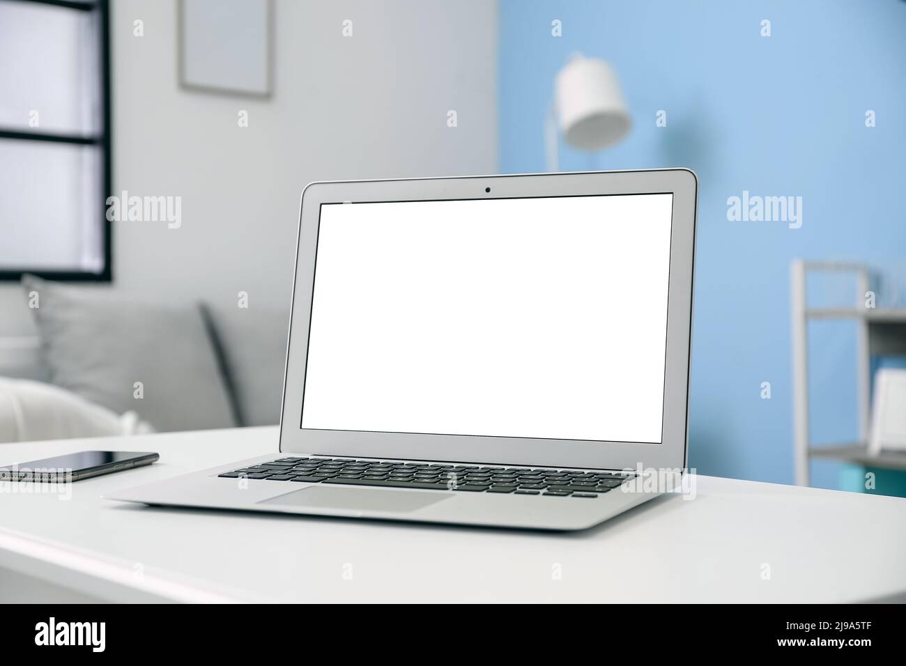 Modern laptop and mobile phone on table in room Stock Photo - Alamy