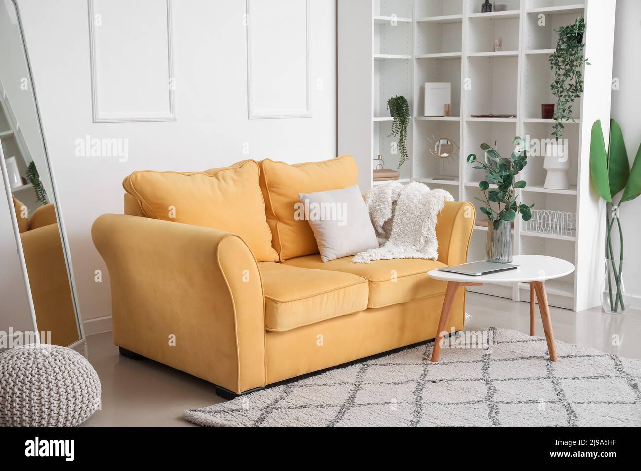Interior of light living room with yellow sofa and eucalyptus in vase ...