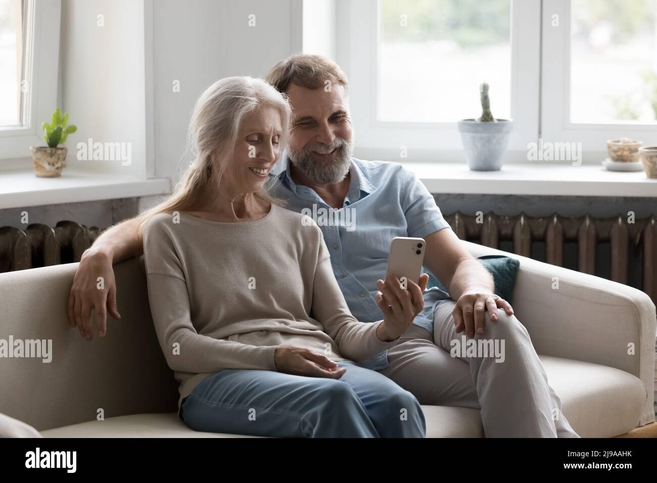Happy elder married couple using mobile phone at home Stock Photo - Alamy