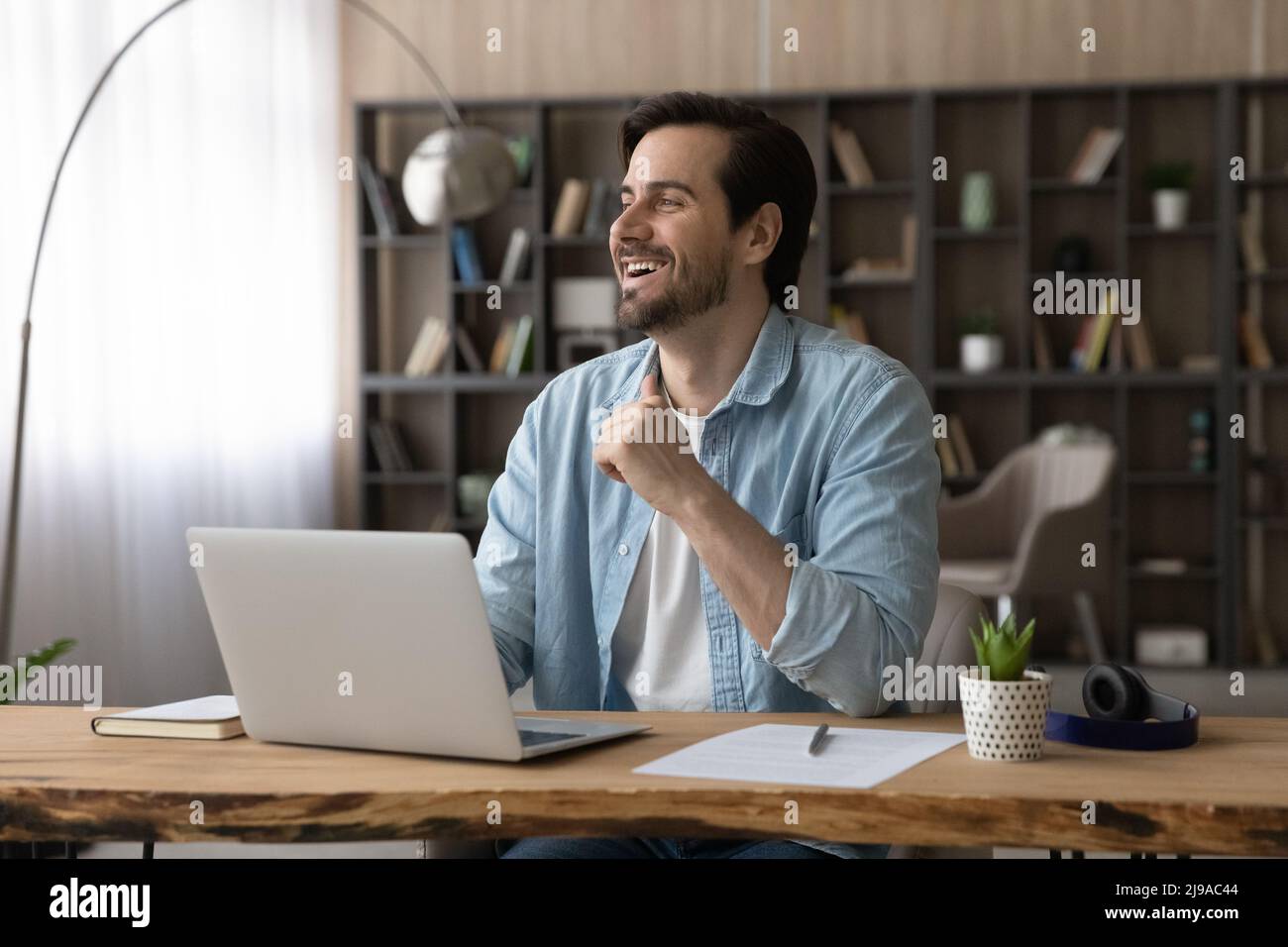 Glad young male sit at desk look above pc screen Stock Photo - Alamy
